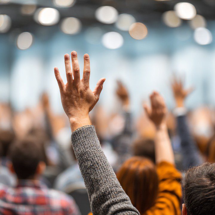 Audience Members Raising Hands at a Seminar - PresentationGO